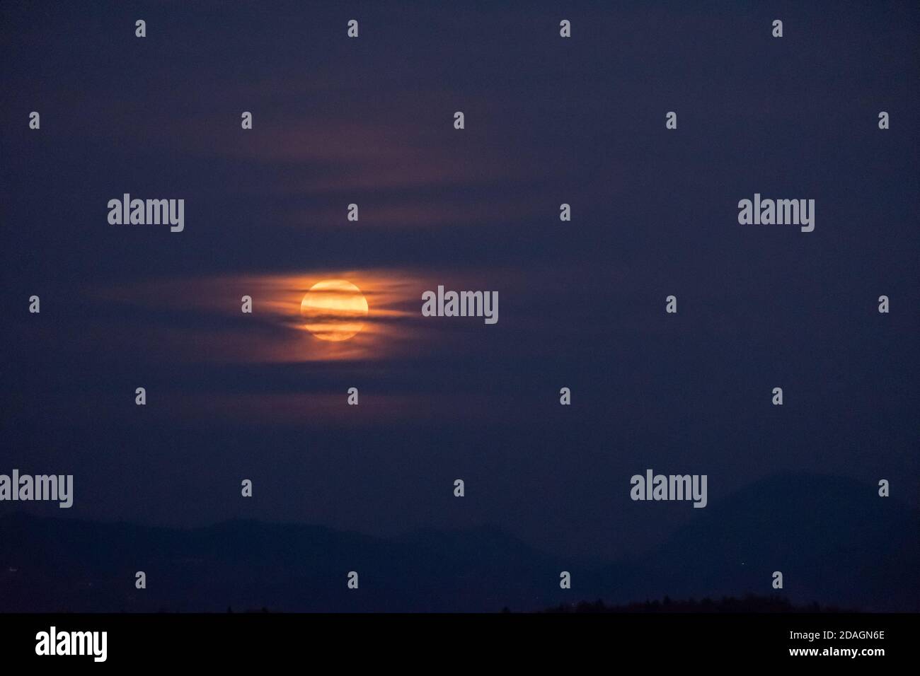 huge orange full moon peeking through misty clouds illuminating the ...