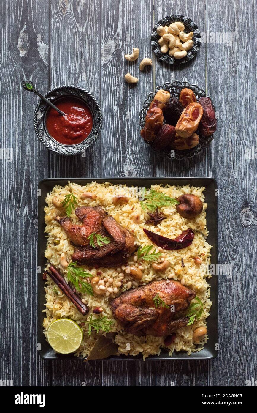 Chicken Mandi with dates on a black table. Arabic cuisine. Top view ...