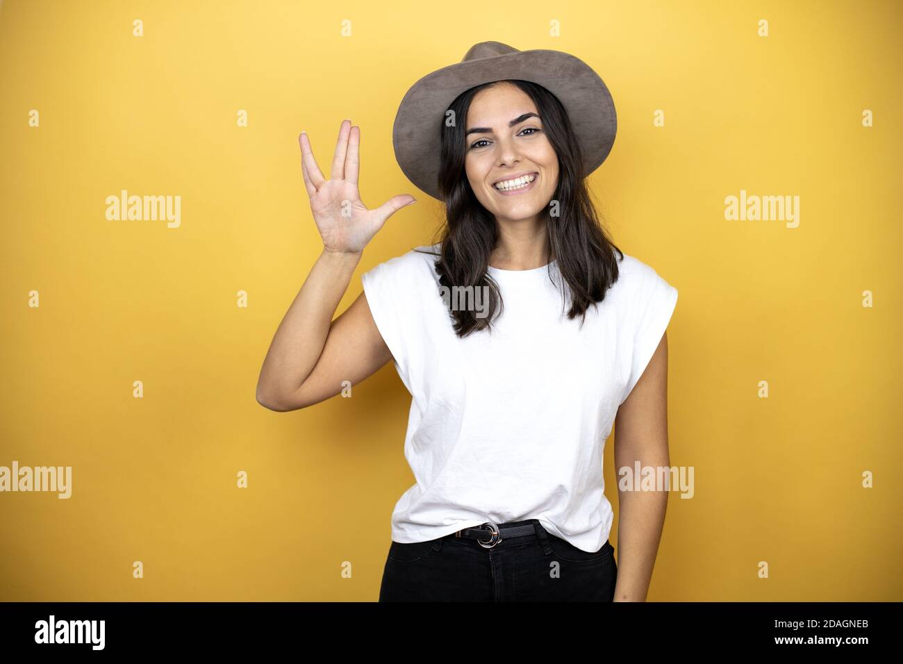 Beautiful woman wearing casual white t-shirt and a hat standing over ...