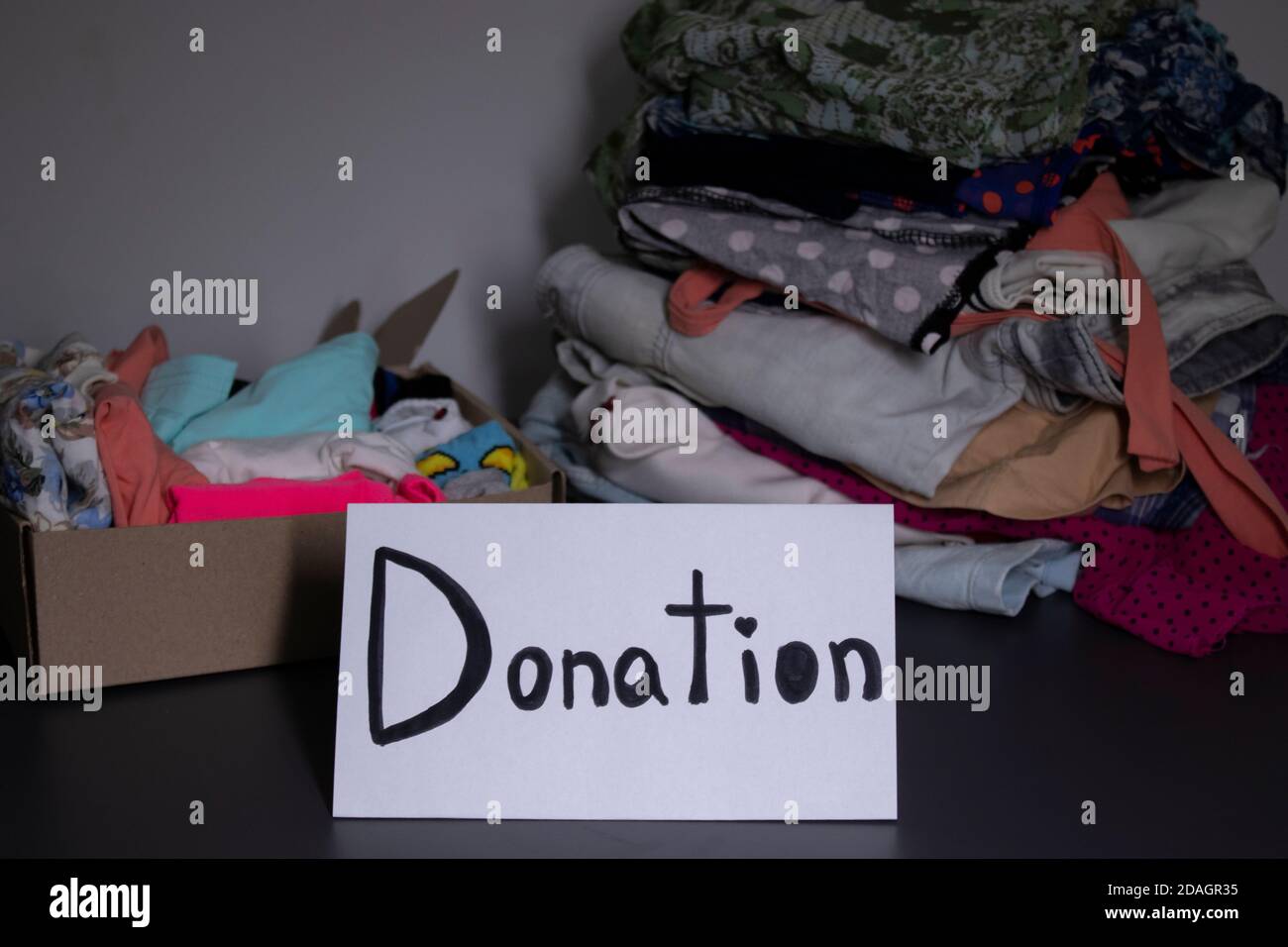 'donation' sign handwritten with black letters. A box with clothes and ...