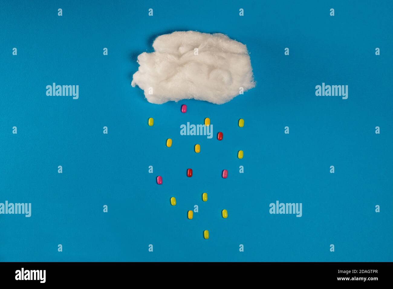 Cloud made of foam on blue background with colorful candies as rain ...