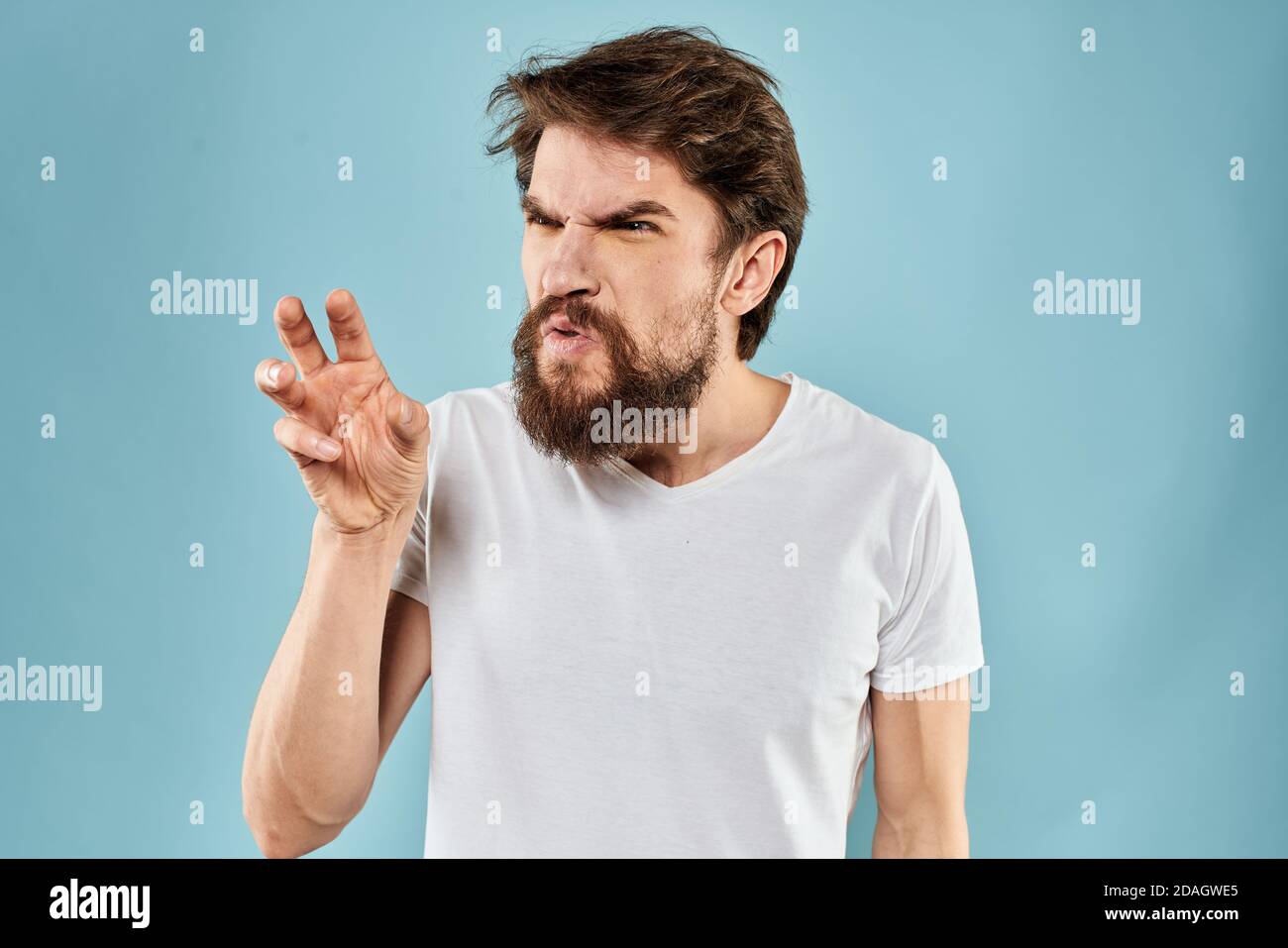 Bearded man in white T-shirt emotions gestures with hands displeased ...