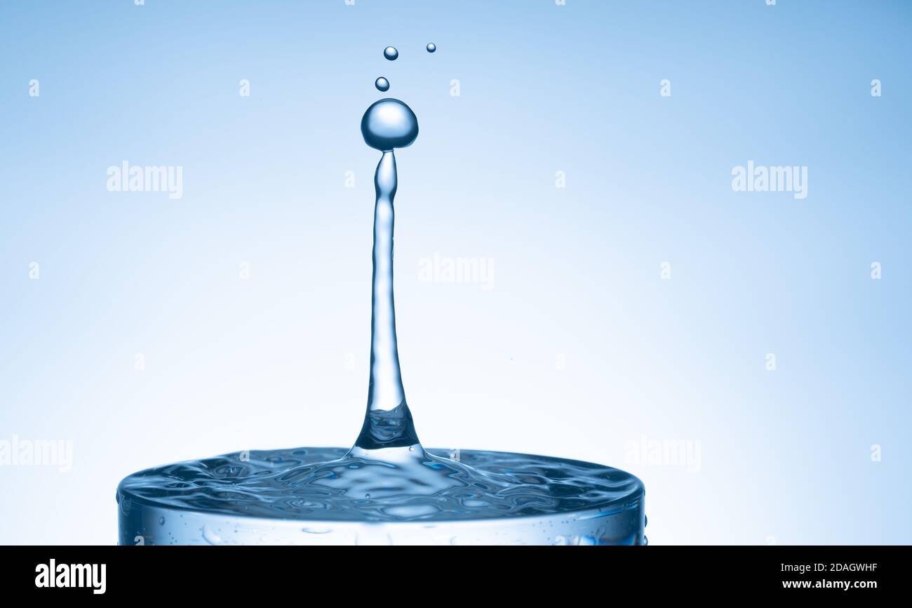 Water drop splashing into glass from isolated bright background Stock ...