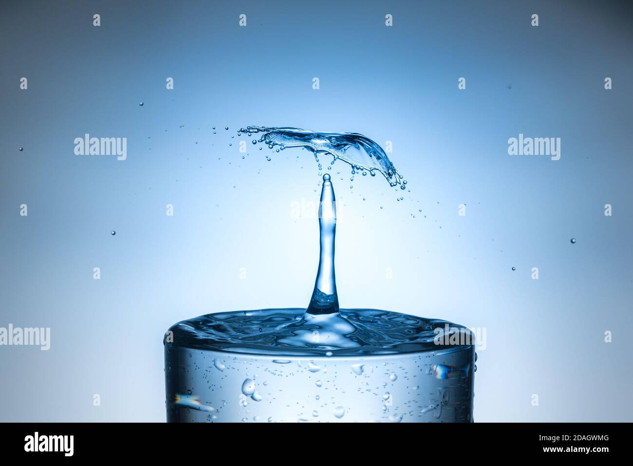 Water drop splashing into glass from isolated bright background Stock ...