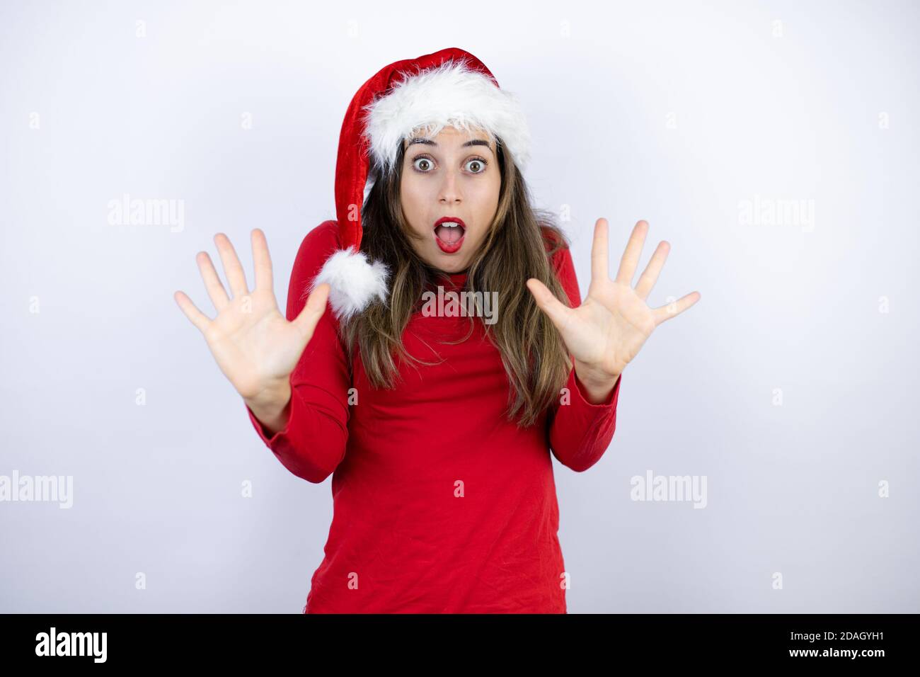 Young beautiful woman wearing a Santa hat over white background afraid ...