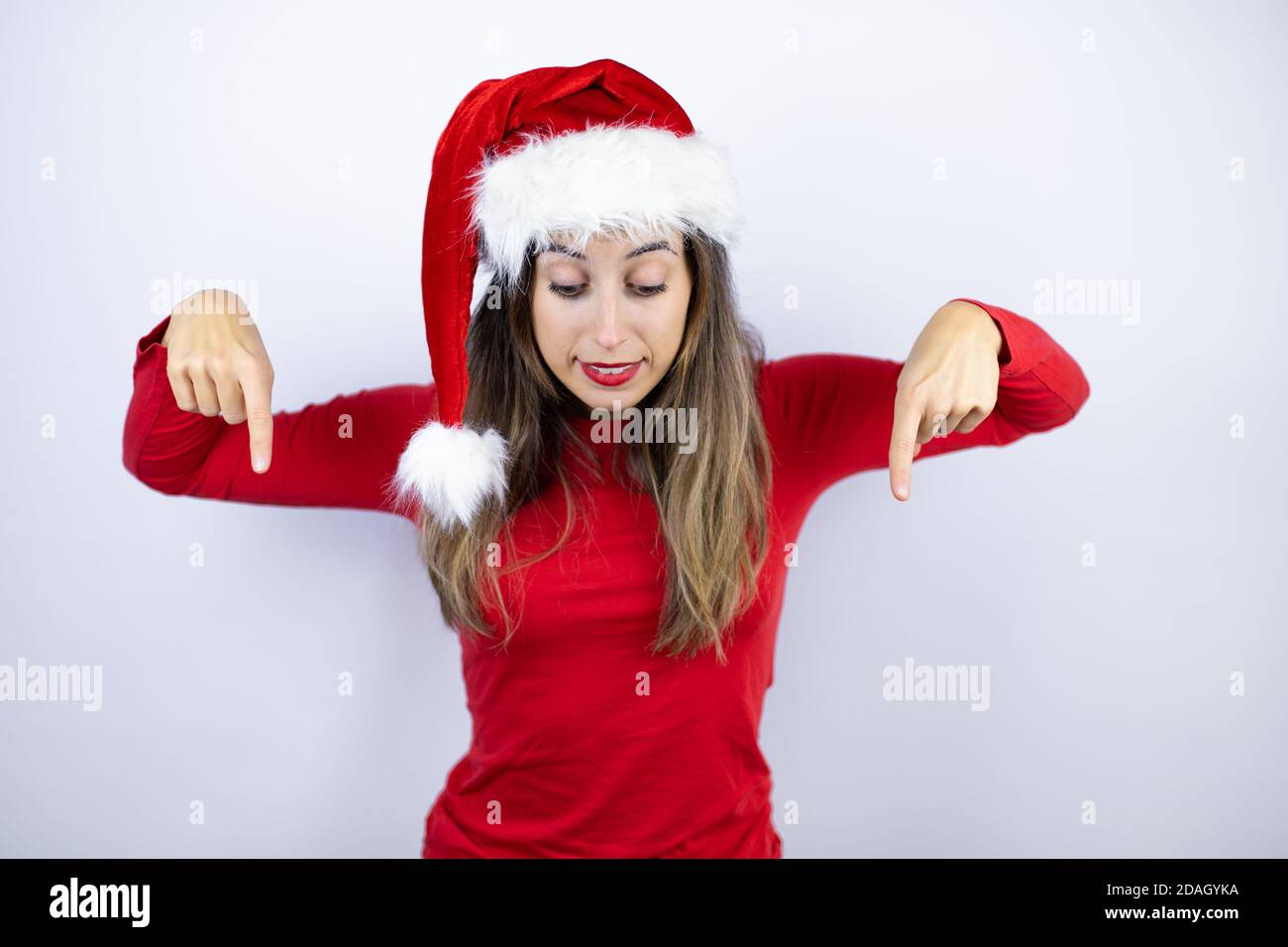 Young beautiful woman wearing a Santa hat over white background ...