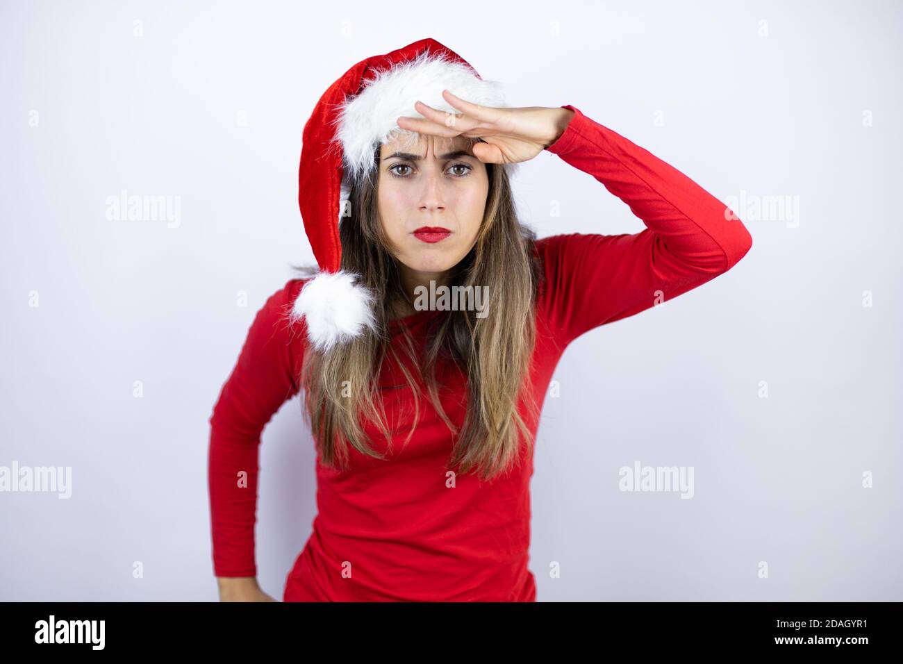 Young beautiful woman wearing a Santa hat over white background very ...