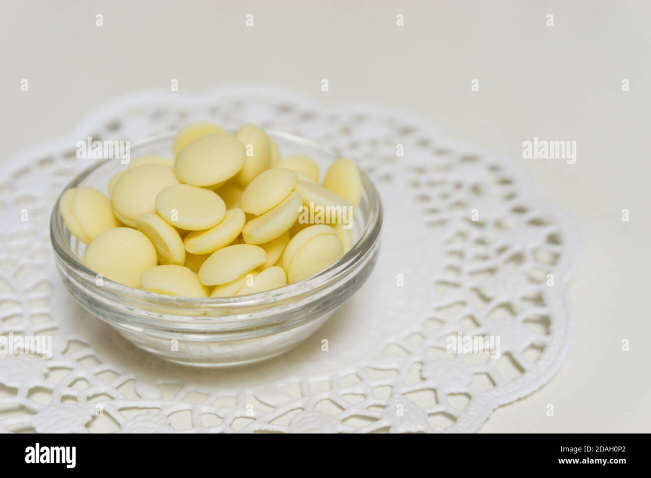Many white chocolate pellets in a glass bowl on white background Stock ...