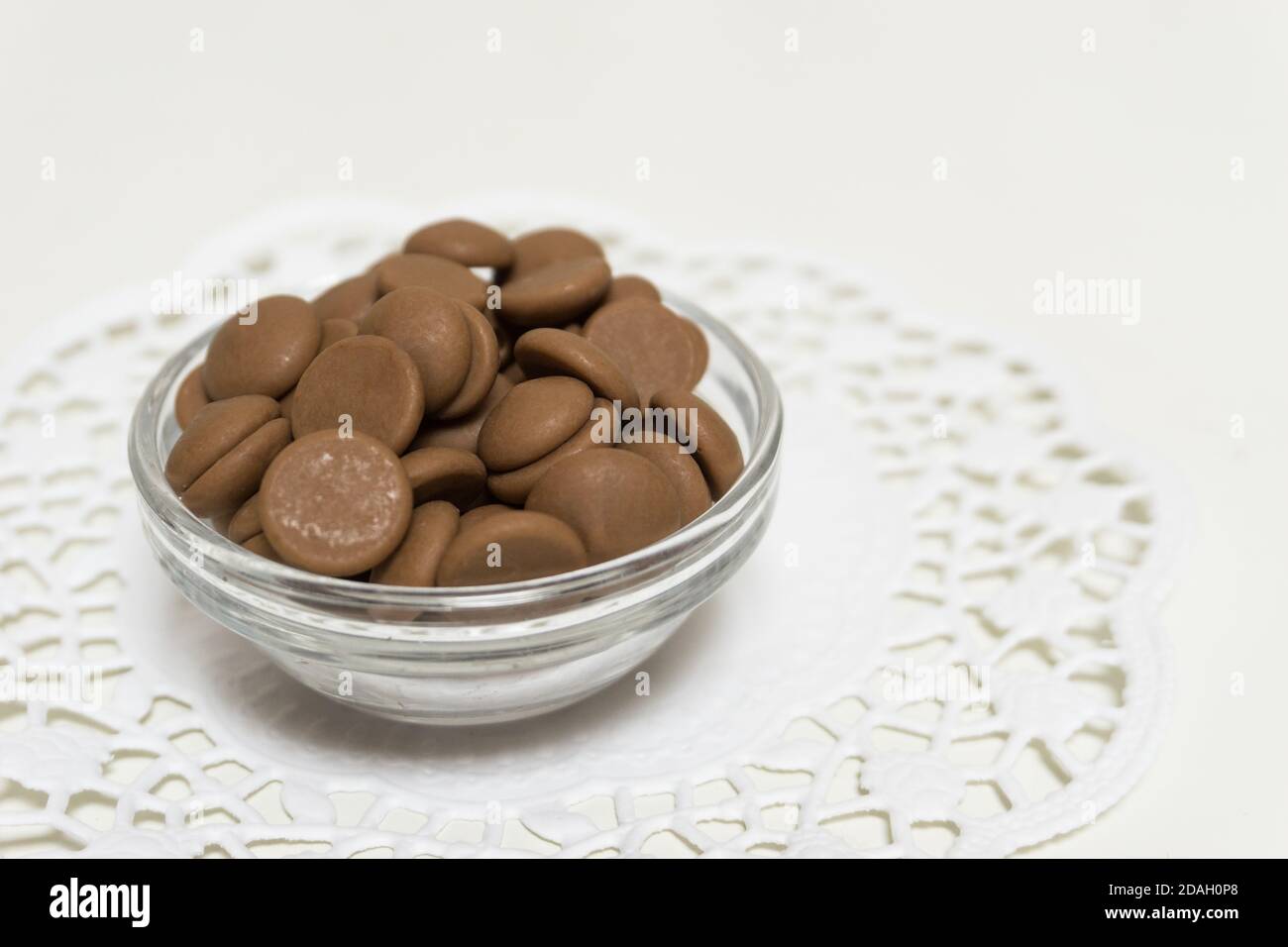 Many brown chocolate pellets in a glass bowl on white background Stock ...