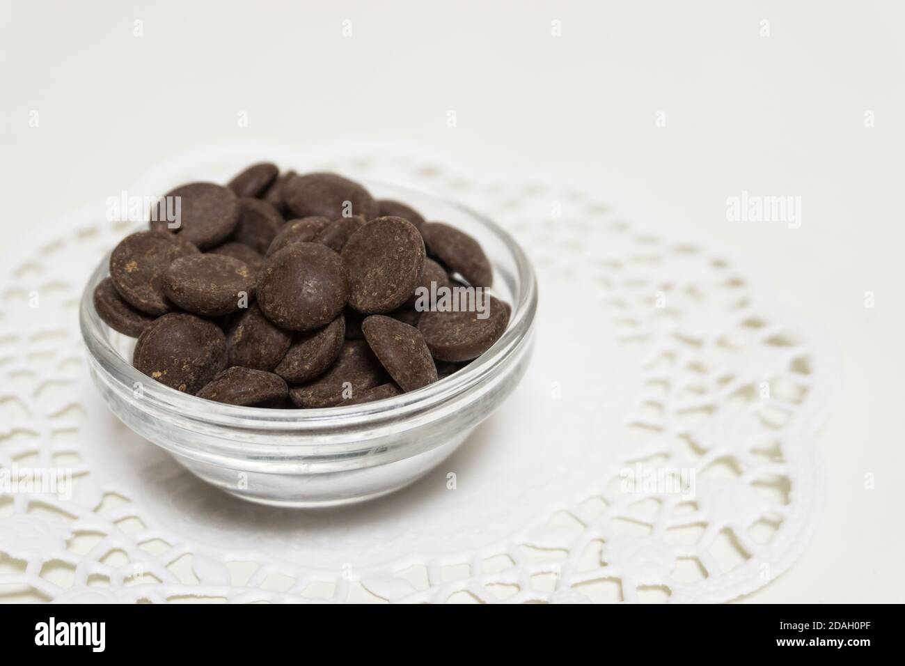 Many brown chocolate pellets in a glass bowl on white background Stock ...