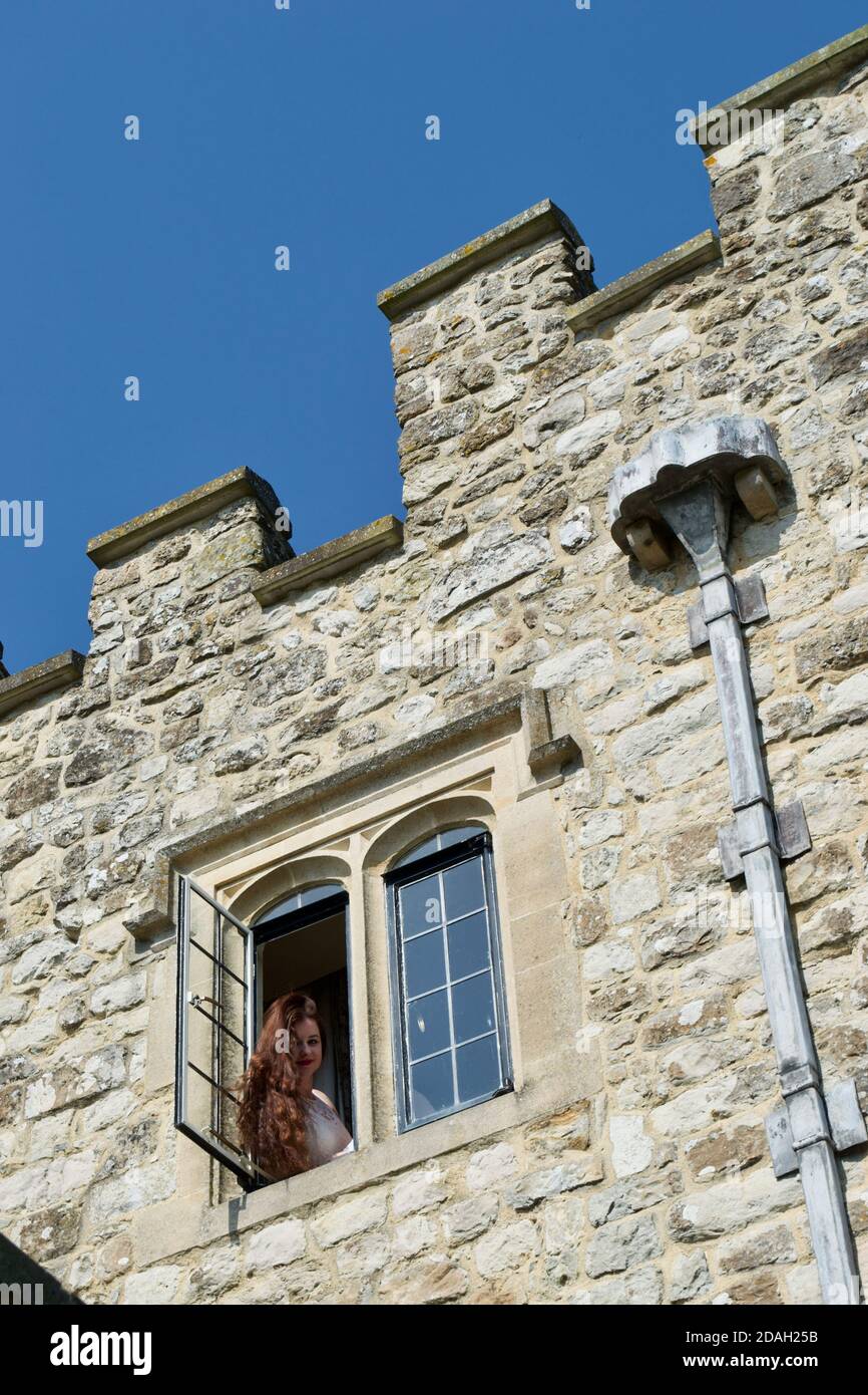 A young lady leaning from a window like Rapunzel, showing her long ...