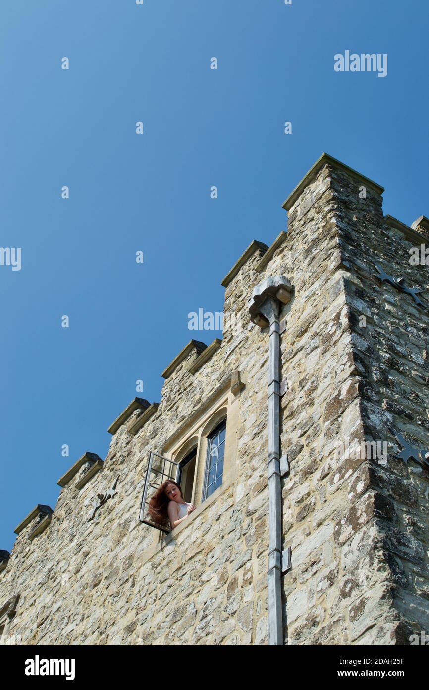 A young lady leaning from a window like Rapunzel, showing her long ...