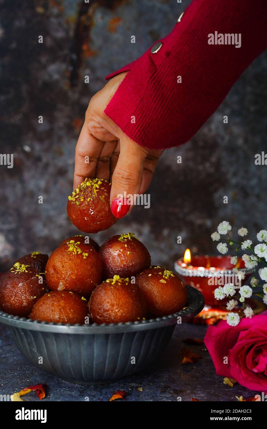 Female hand picking Gulab Jamun/ Diwali sweets, selective focus Stock ...