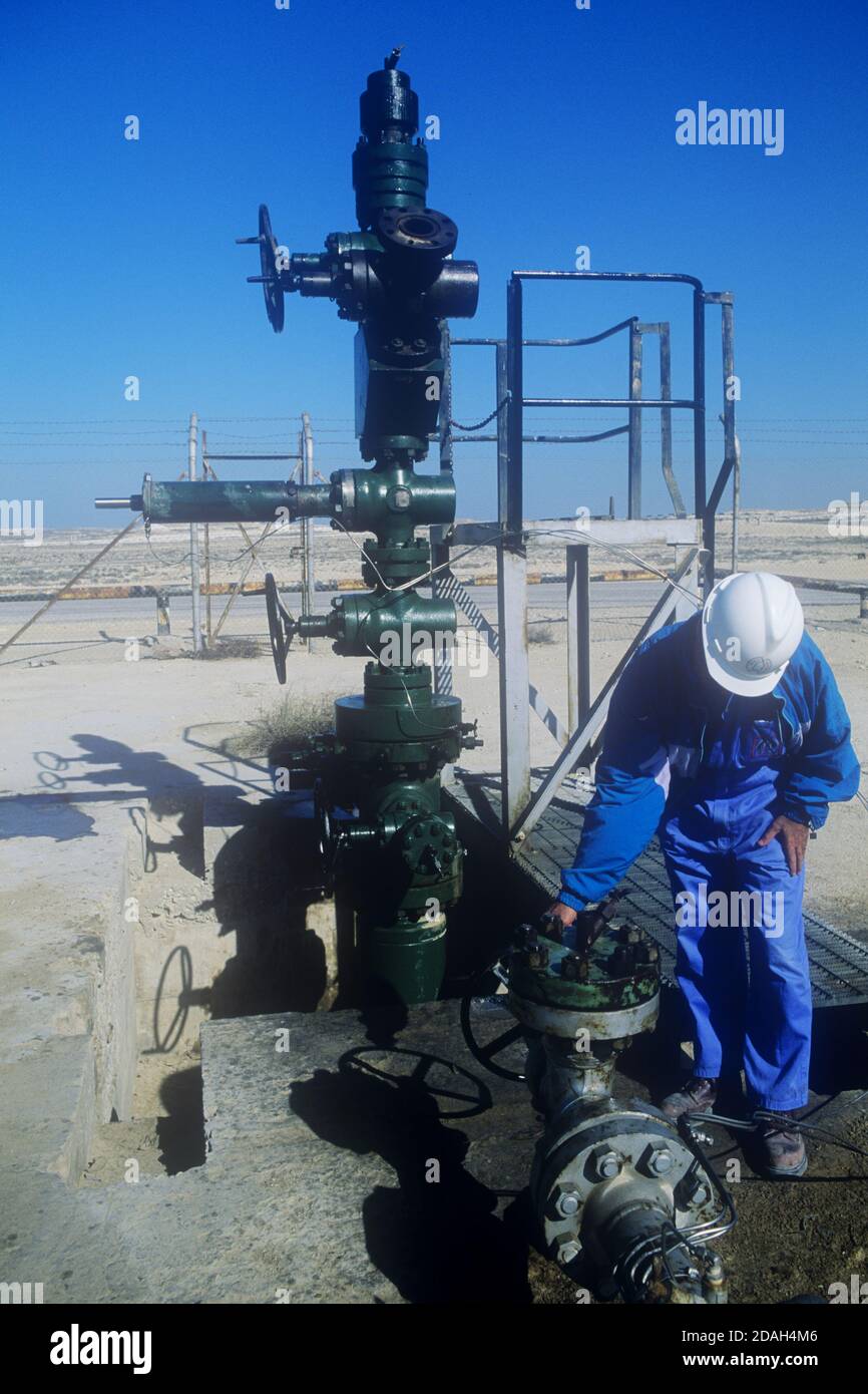 Engineer checking an oil well head, onshore Dukhan Field, Qatar 1995 ...