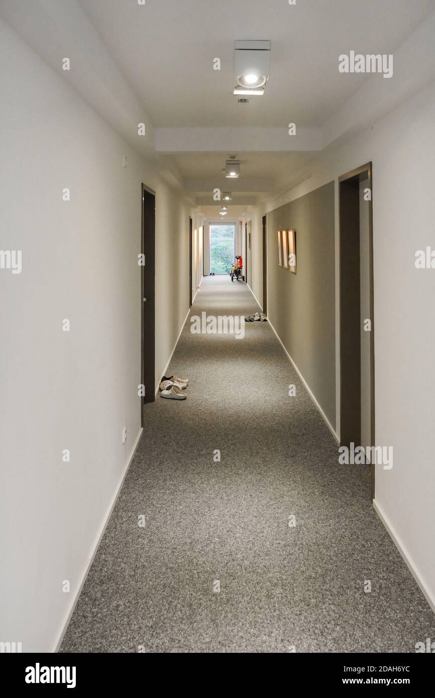 Long building corridor with window at vanishing point end. Vertical ...