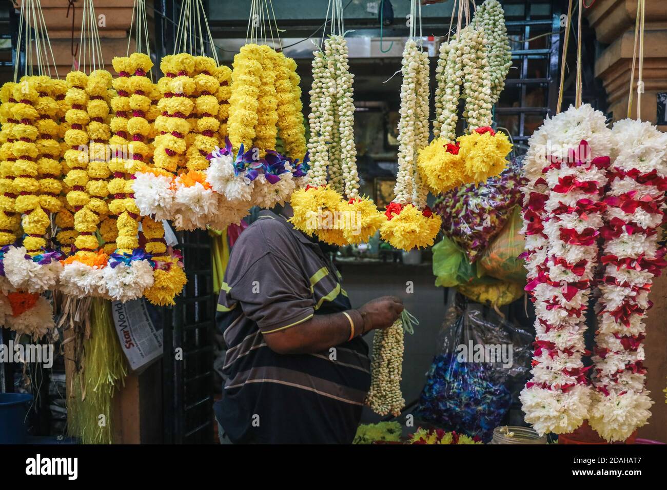 An Indian trader prepares garlands ahead of the Diwali celebration ...