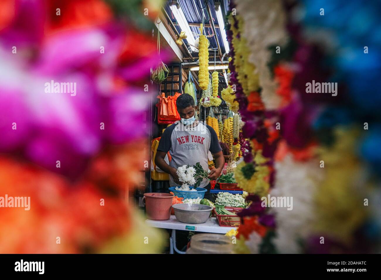 An Indian trader wearing a face mask as a preventive measure prepares ...