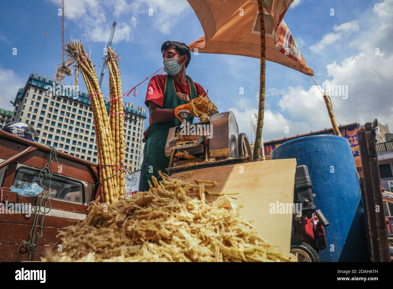 An Indian vendor wearing a face mask as a precaution sells sugarcane ...
