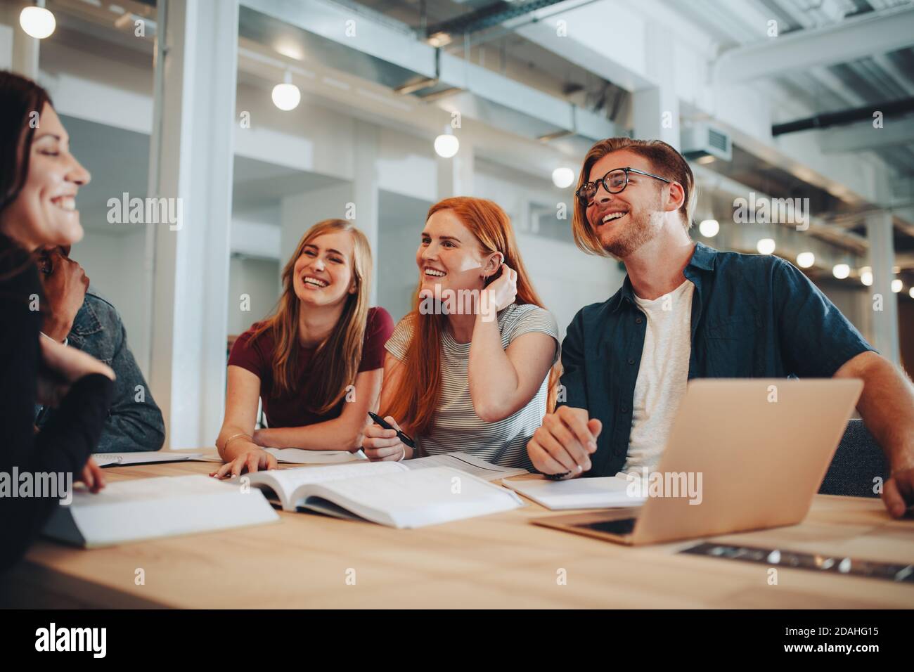 Happy young university students studying with books and laptop in ...