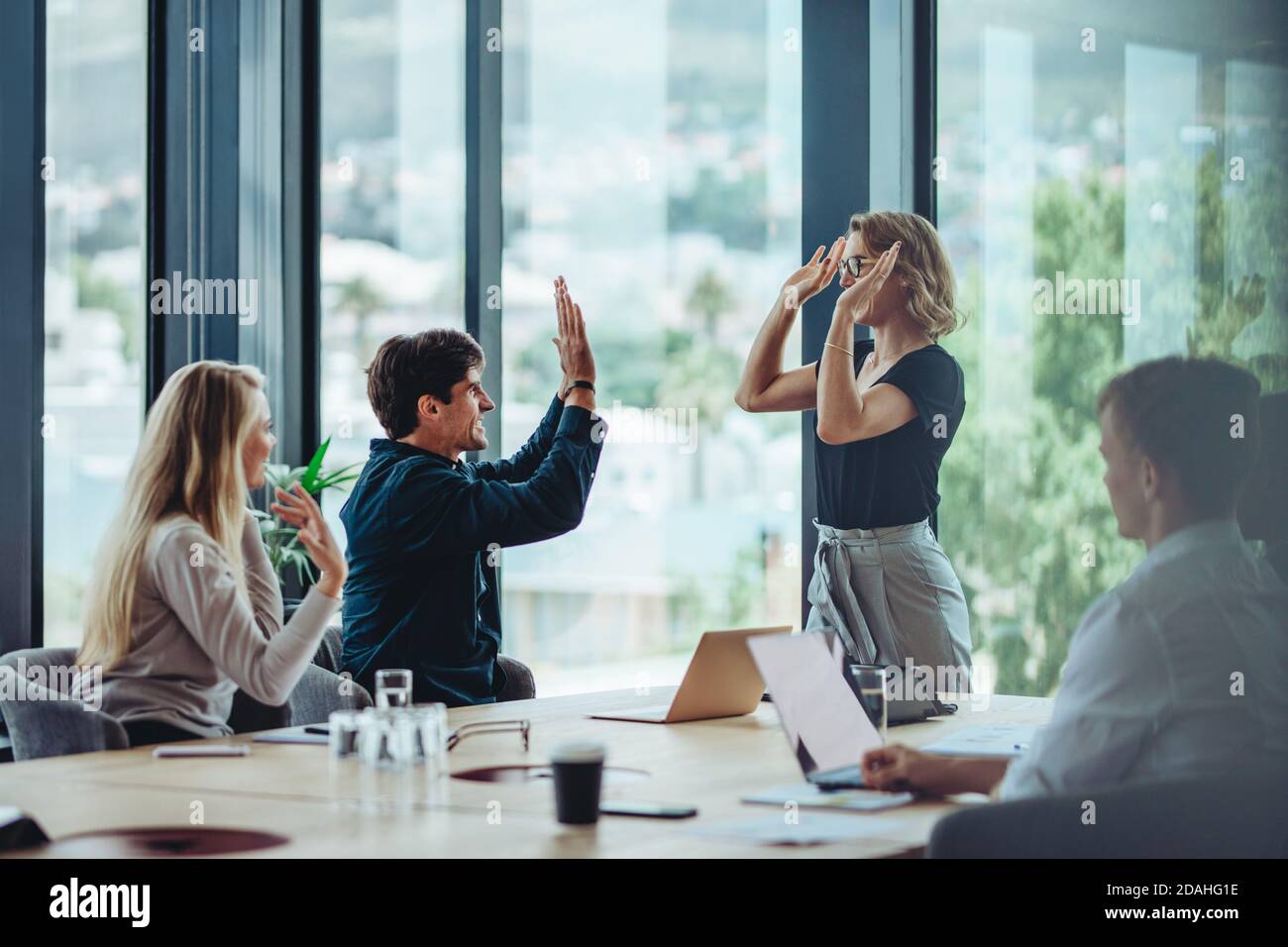 Two colleagues giving high five in meeting. business people celebrating ...