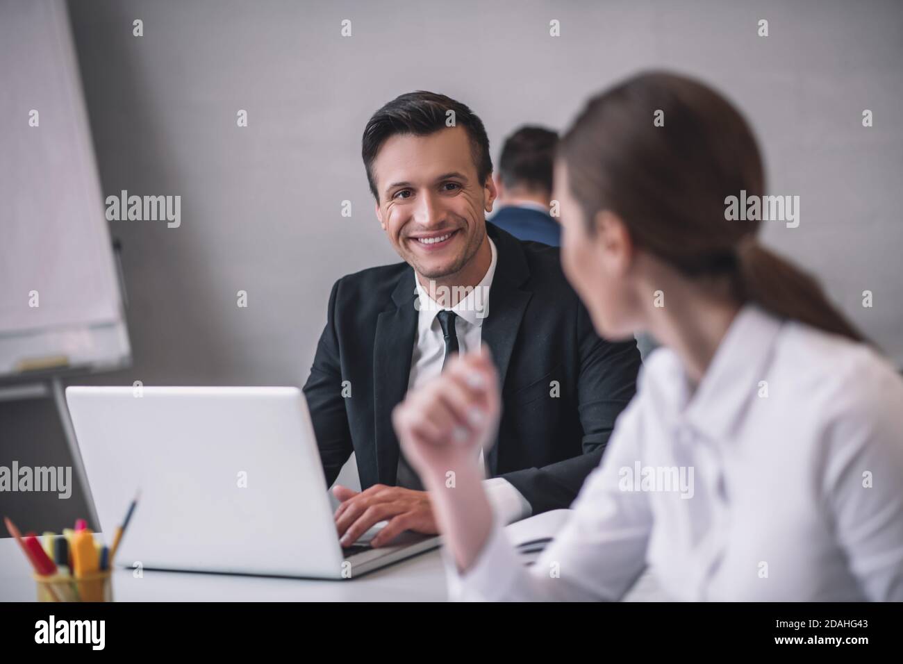 Smiling man behind laptop and woman sitting with back Stock Photo - Alamy