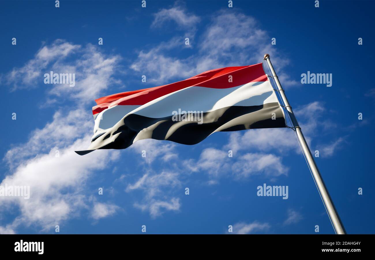 Beautiful national state flag of Yemen fluttering at sky background ...