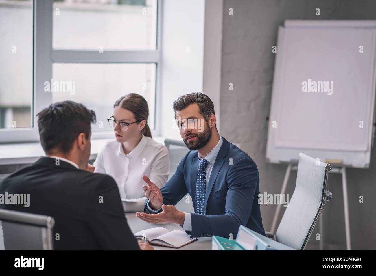 Two business men communicating at table and woman Stock Photo - Alamy
