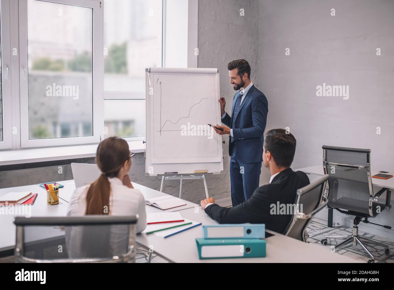 Man in suit giving presentation and two colleagues Stock Photo - Alamy