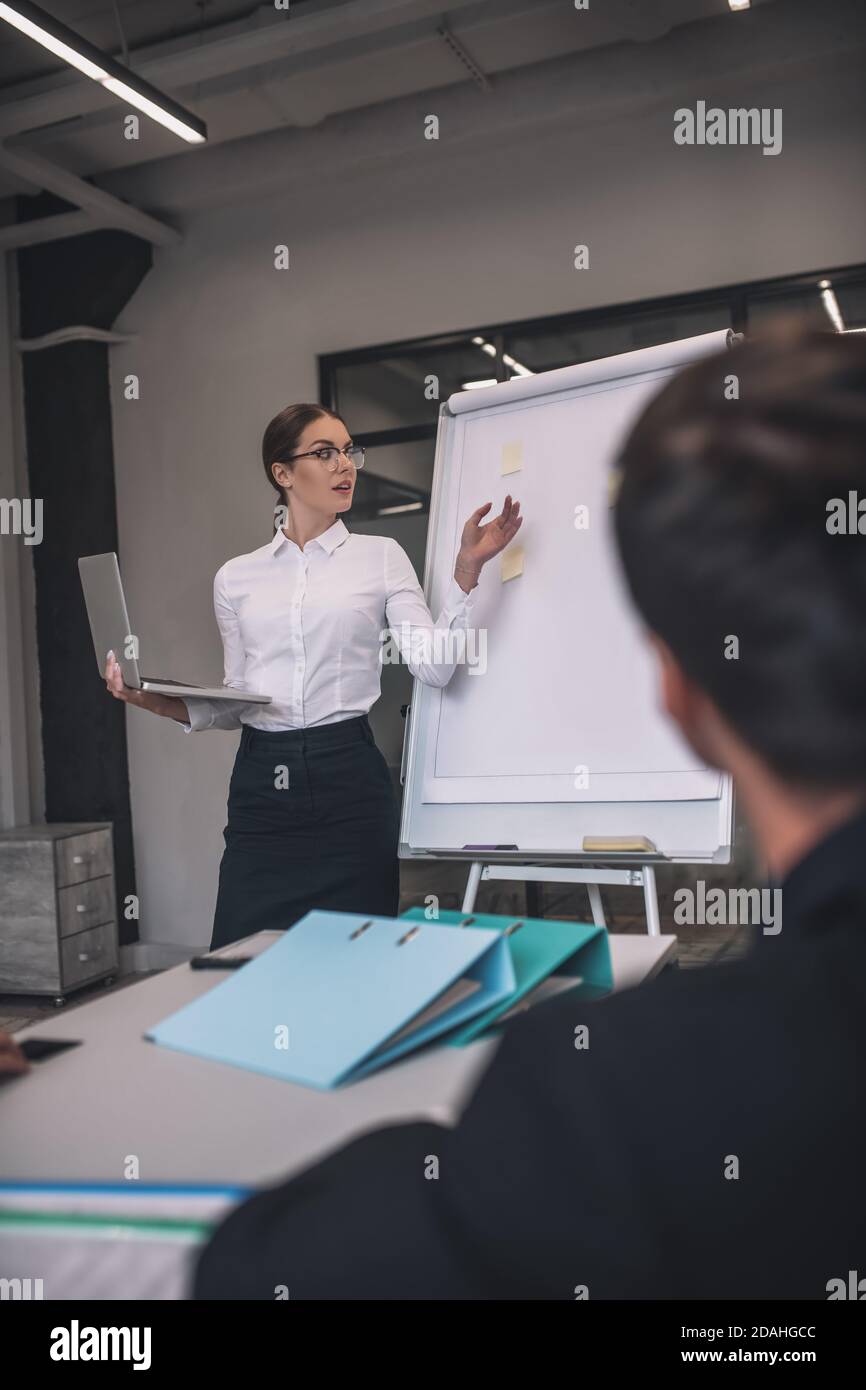 Brown-haired female standing near flipchart, delivering presentation ... Brown-haired female standing near flipchart, delivering presentation ...