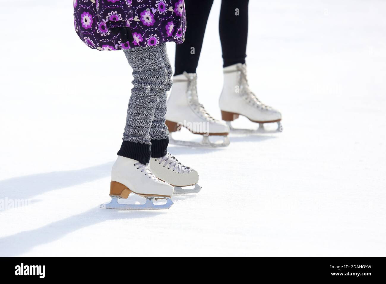 the legs of an adult and child skating on the ice rink Stock Photo - Alamy