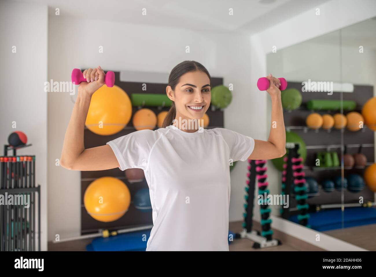 Pretty dark-haired female working out with dumbbells in the gym Stock ...