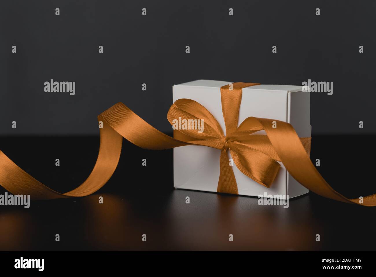 Close-up view of white gift box with elegant gold ribbon in luxury bow ...