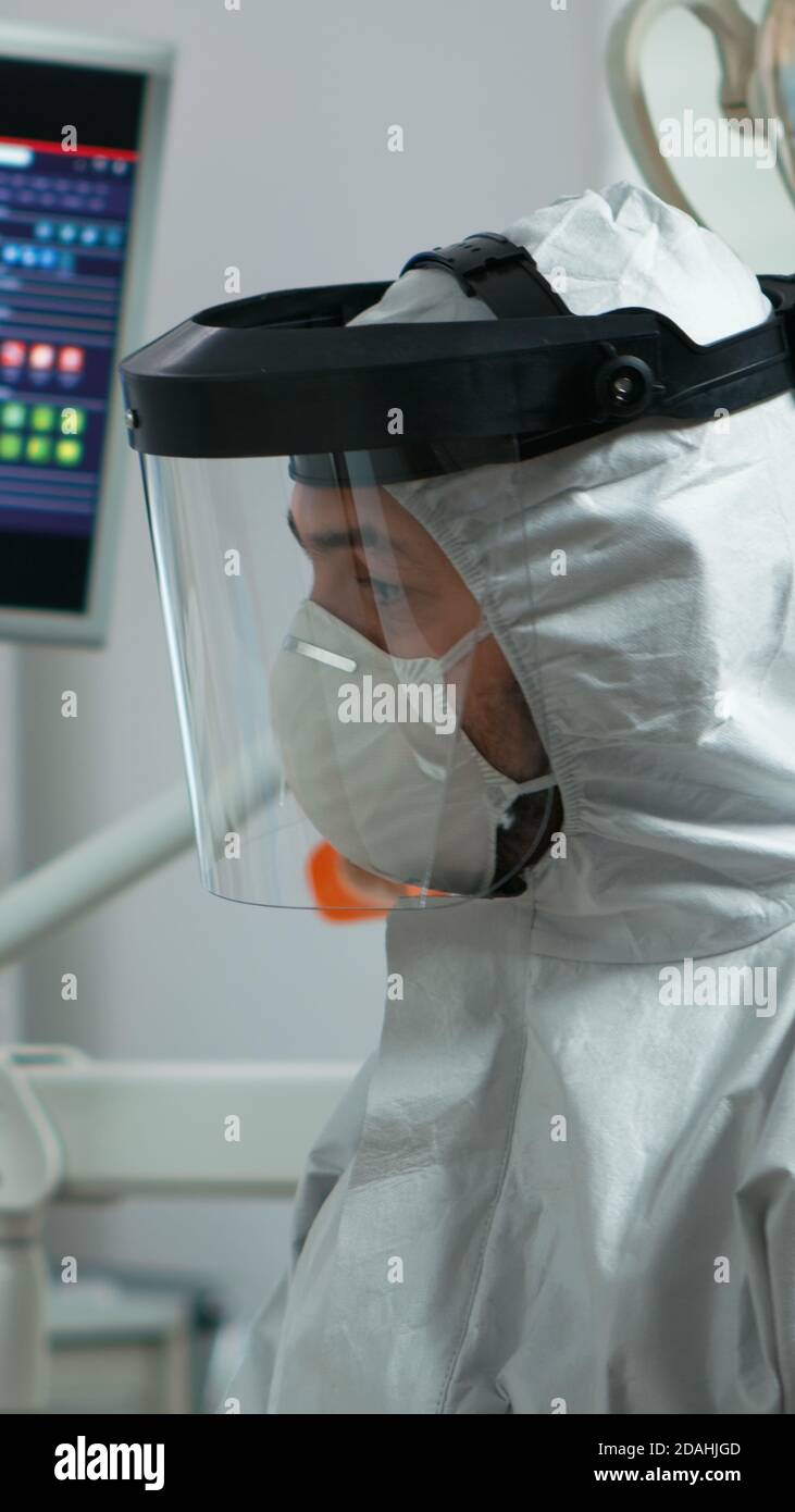 Orthodontist in protection coverall speaking hi-res stock photography ...