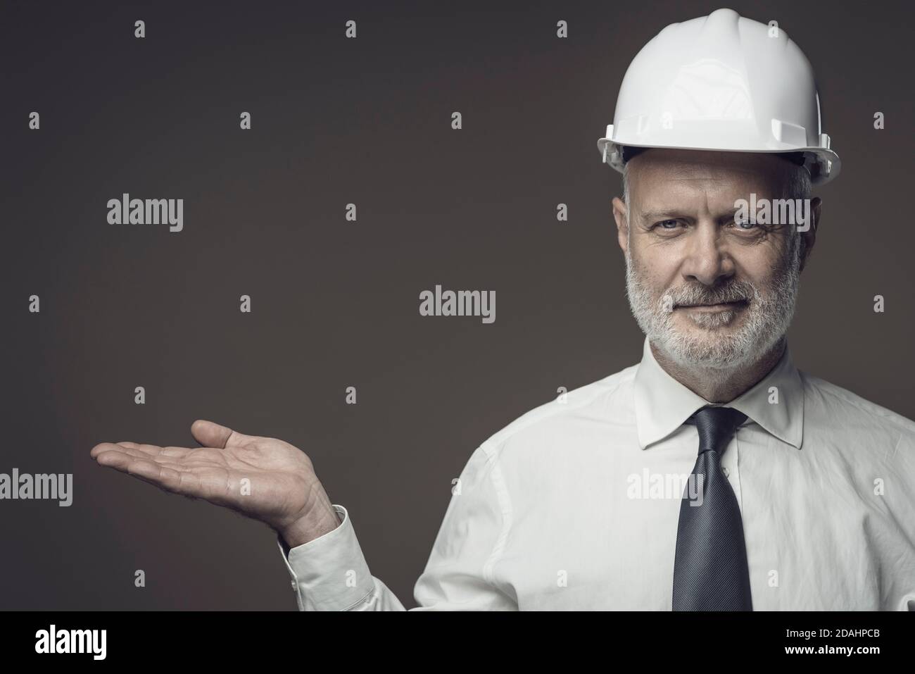 Smiling middle-aged businessman and engineer wearing a safety helmet ...