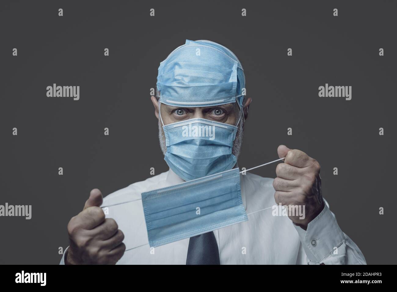 Funny confident businessman wearing many surgical masks and fighting ...