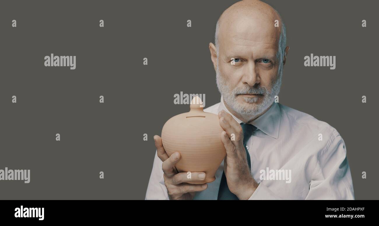 Confident businessman holding a clay money box, investments and funds ...