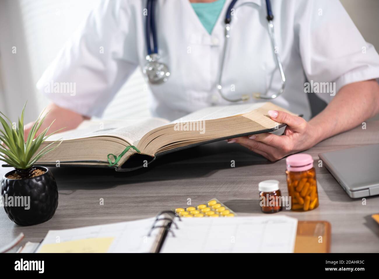 Female doctor reading a textbook in medical office Stock Photo - Alamy