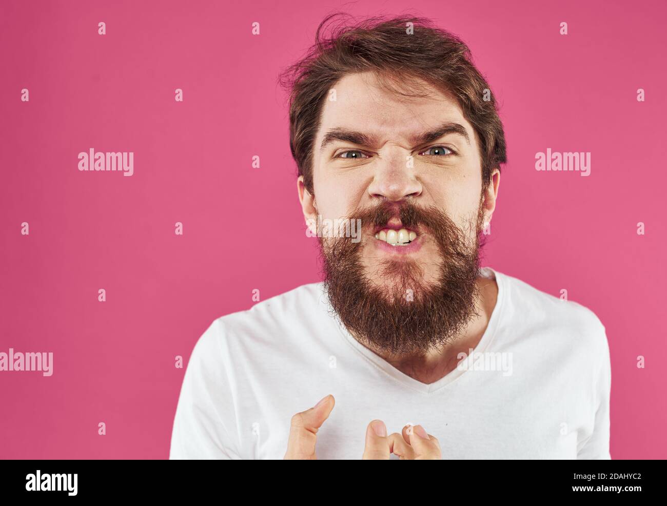An angry man with a bushy beard bared his teeth against a pink ...