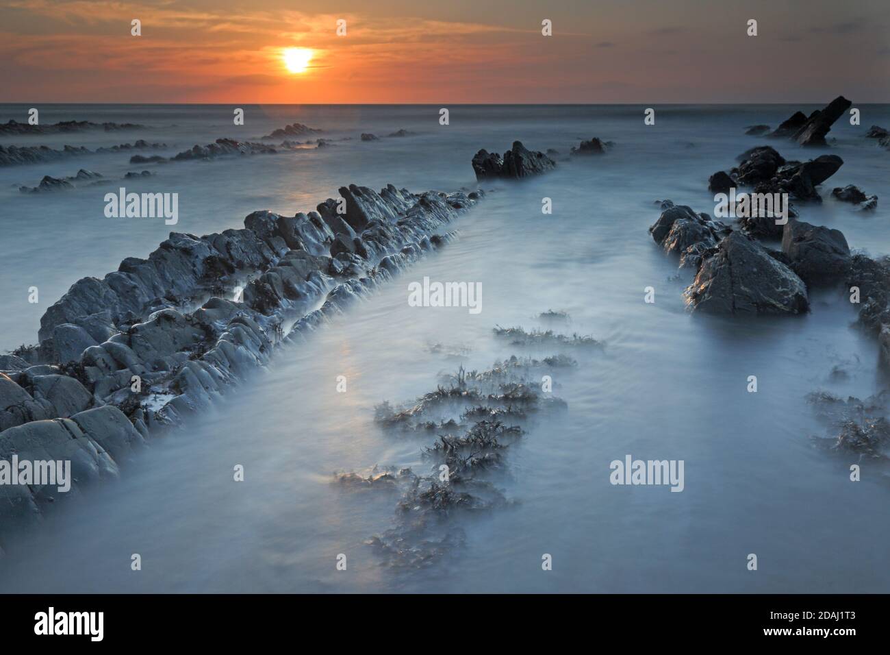 View of the rock ledges at sunset at Welcombe Mouth Beach on the Devon ...