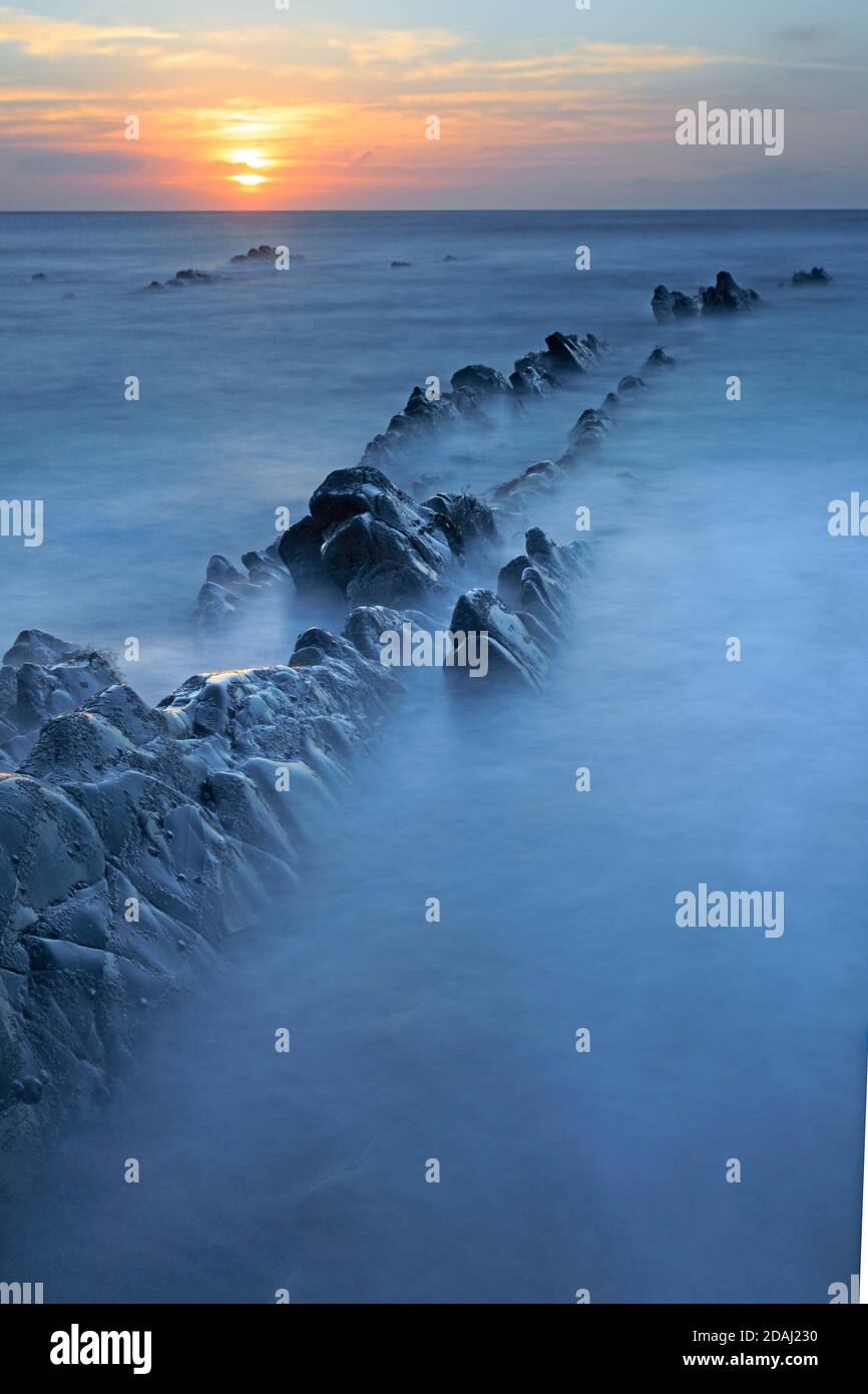 View of the rock ledges at sunset at Welcombe Mouth Beach on the Devon ...