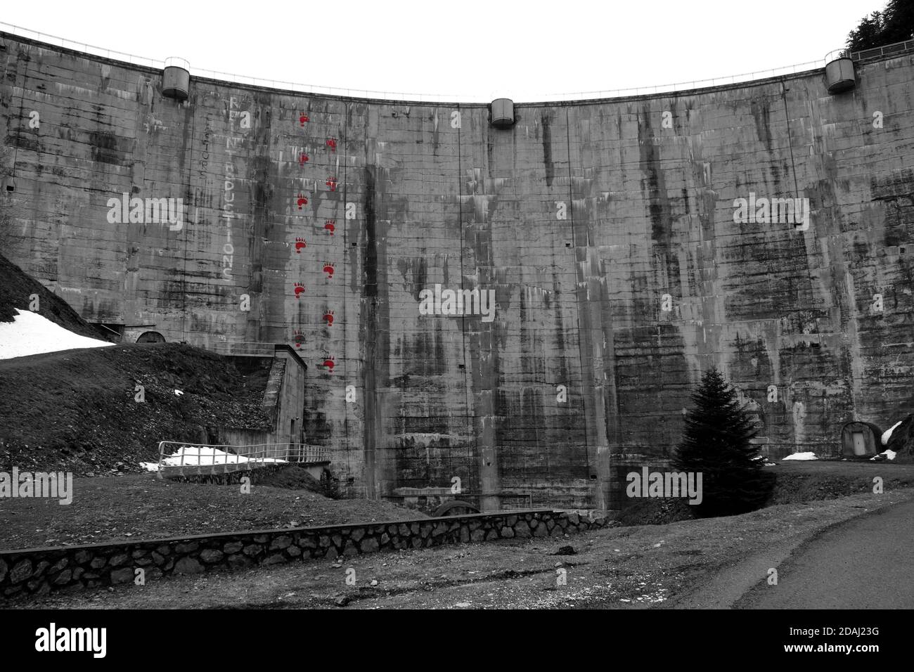 Grayscale shot of a dam wall with red color pop of animal footprints ...