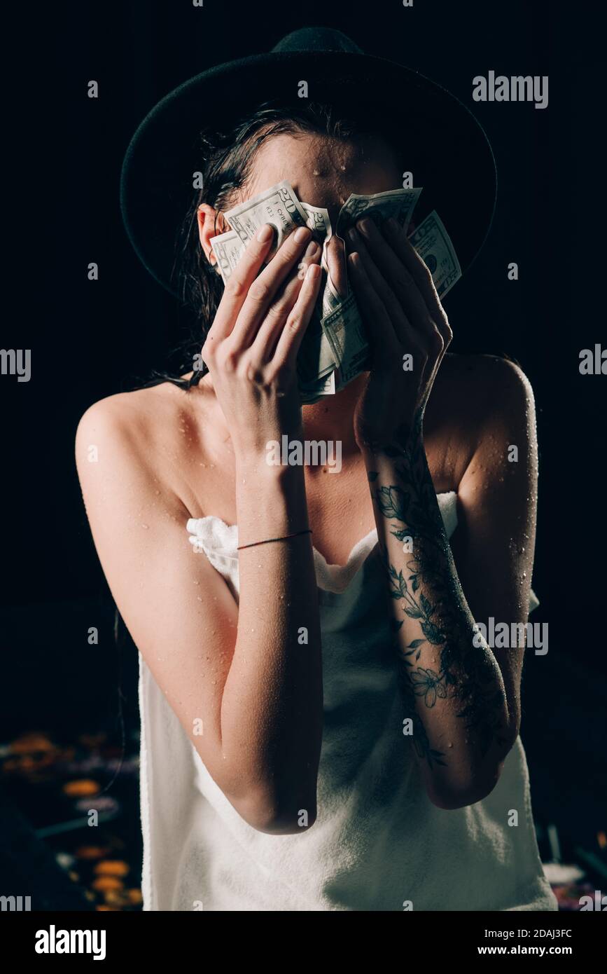 Beautiful woman in a towel and black hat holding dollars and worry for ...