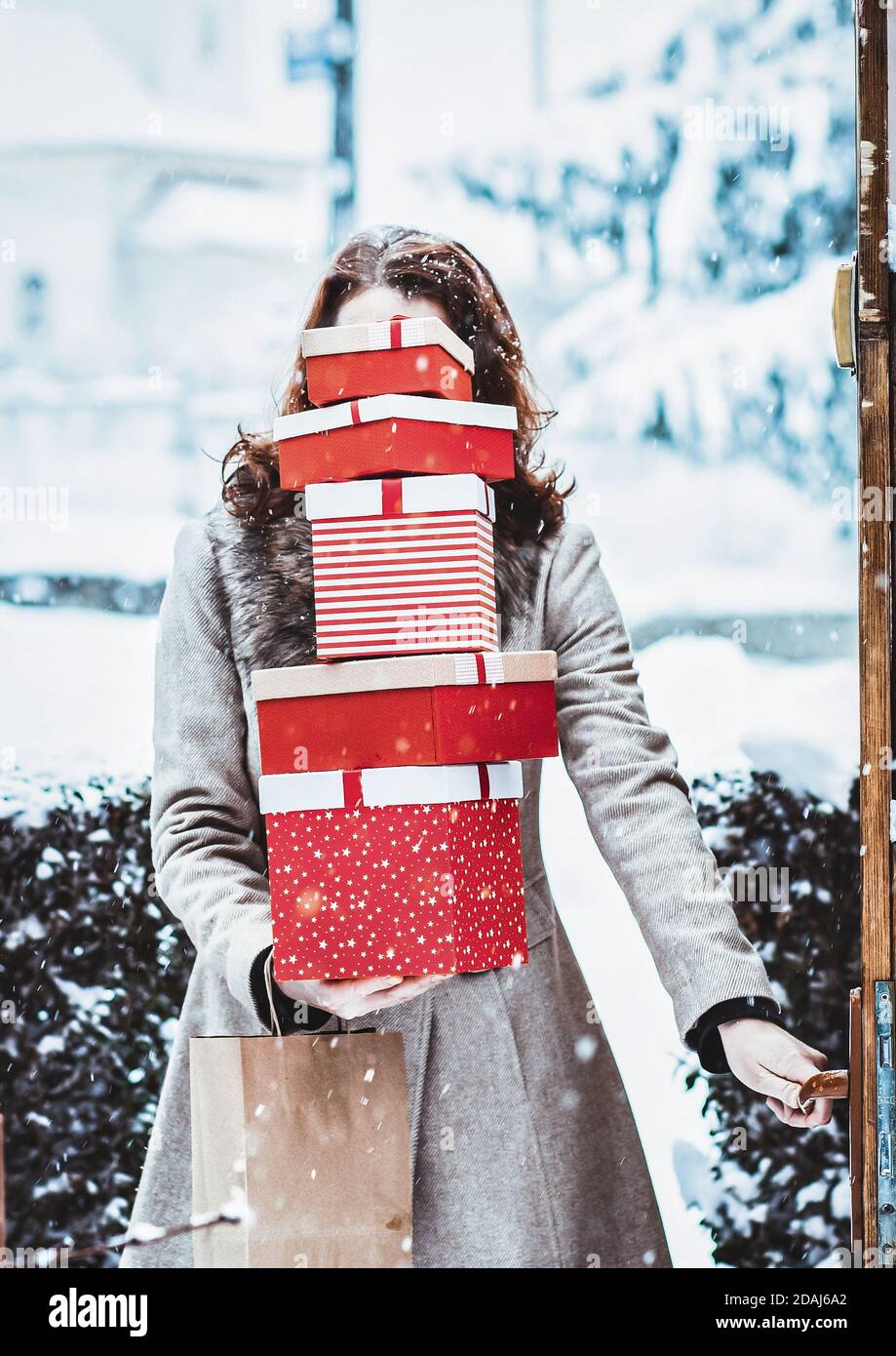 woman returning home from shopping holding pile of christmas present ...