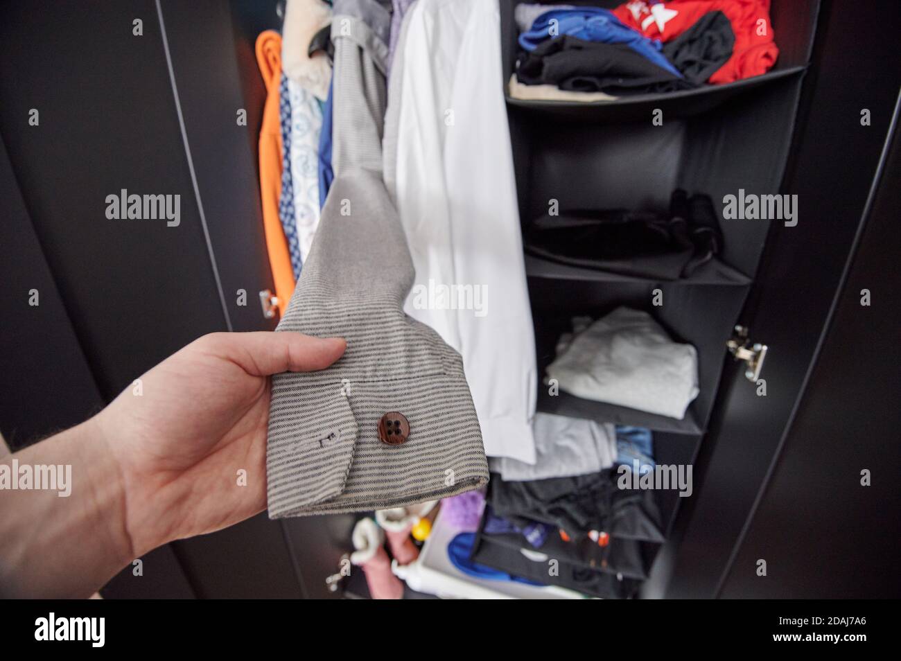 Man getting gray coat from closet. Messy dresser them Stock Photo - Alamy