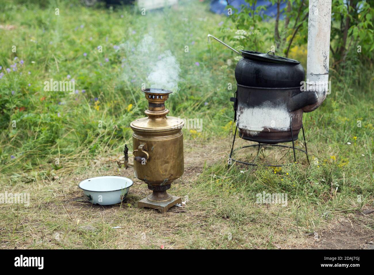 The samovar and the stove with the boiler for food stand on the grass ...