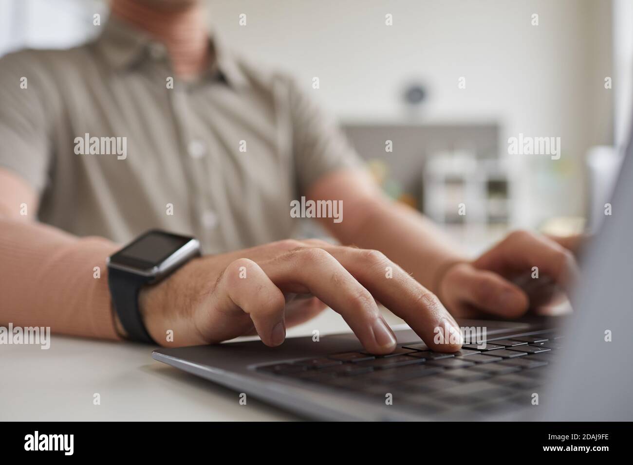 Close-up of man sitting at the table and typing on computer keyboard ...