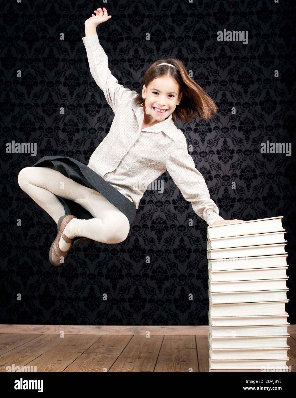 girl jumping through a stack of books on a vintage background Stock ...