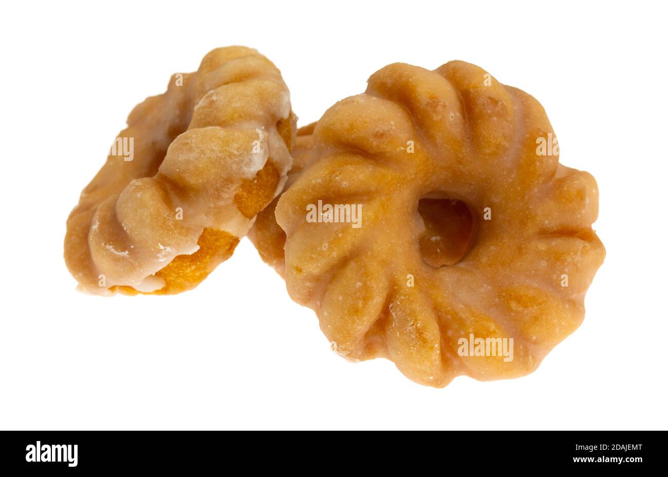 Side view of three glazed bite size crullers on a white background ...