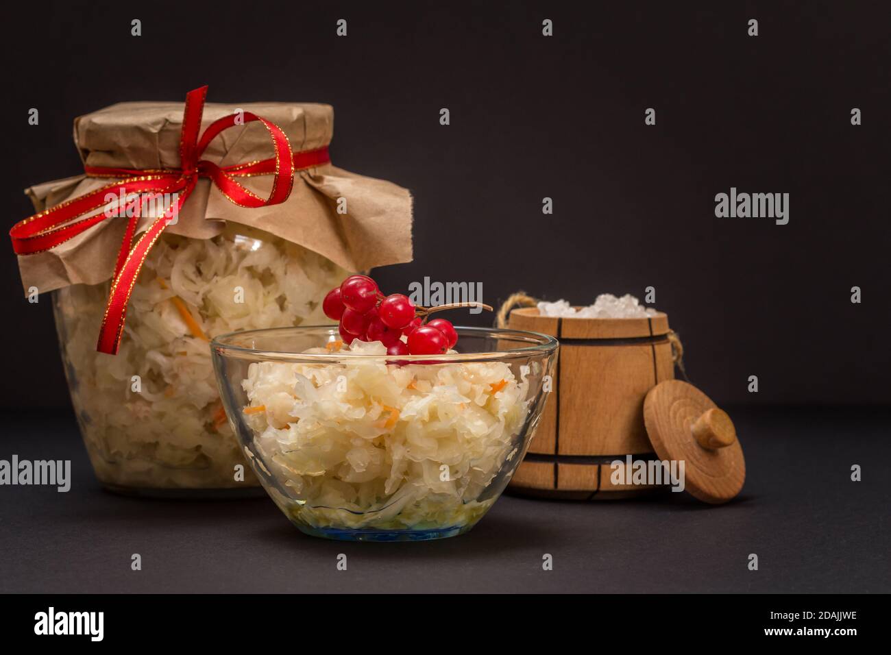 Homemade fermented cabbage in a glass bowl and a jar, salt in a wooden ...