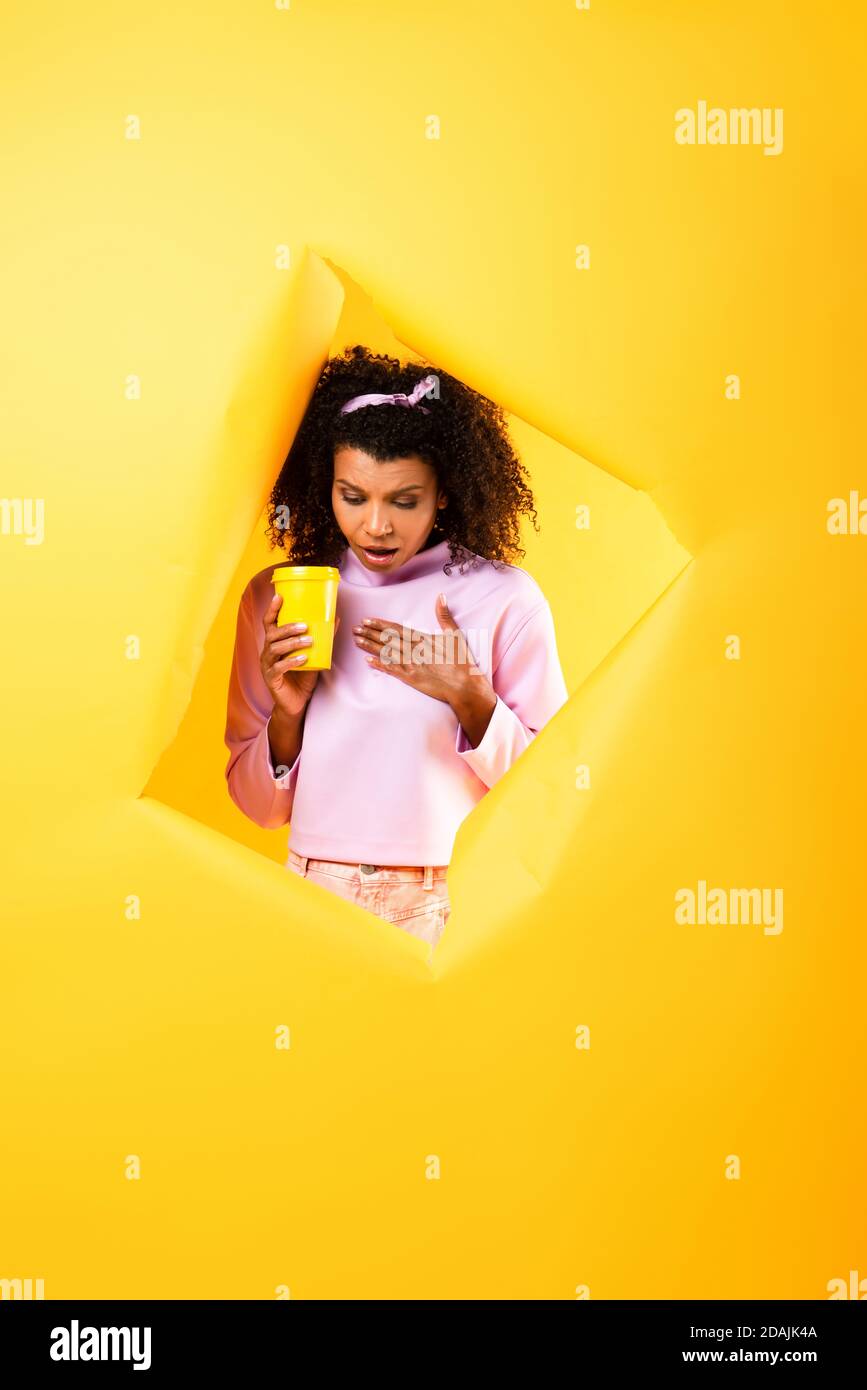 Surprised African American Woman Holding Disposable Cup And Looking